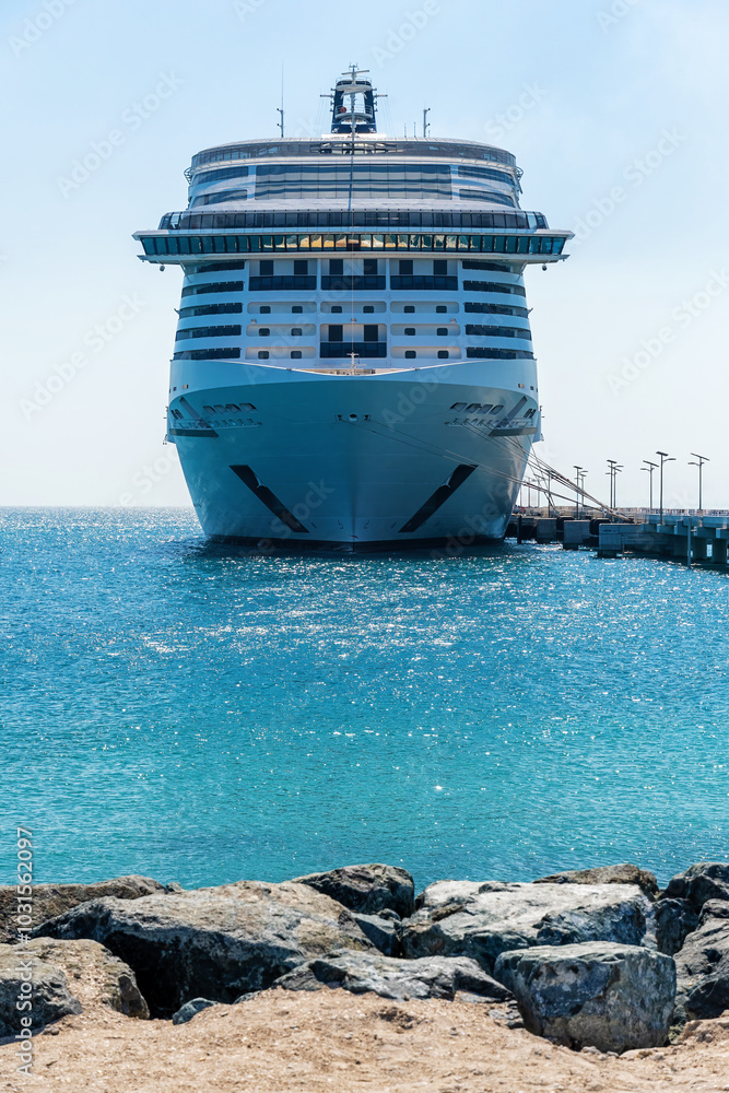 A large cruise ship is docked at a port, with the bow of the ship ...
