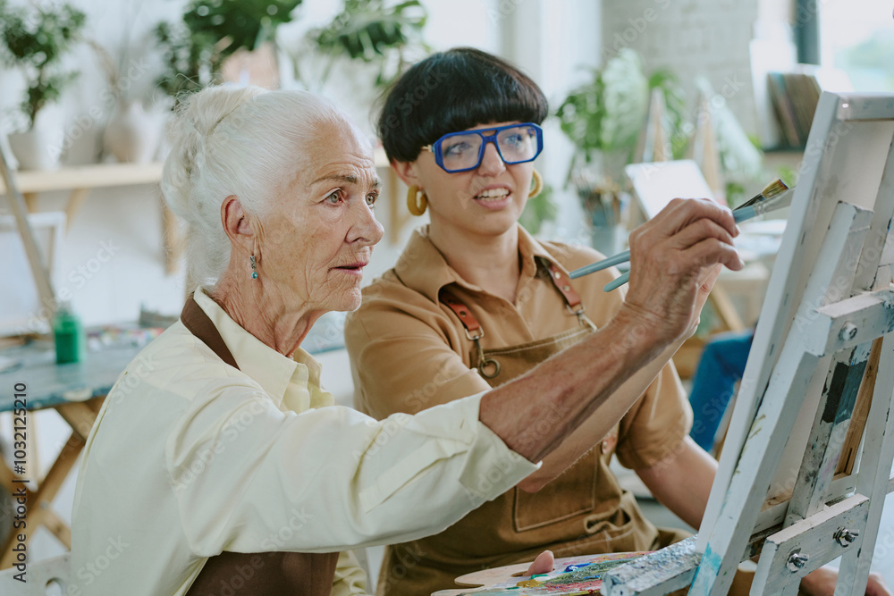 Mature drawing teacher with bob haircut helping her senior student who ...