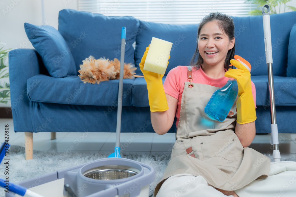 Cheerful asian maid sits on the floor in a cozy living room, ready to ...