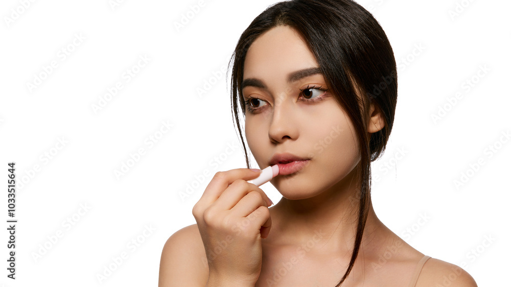 Young Korean woman taking care after lips, applying lip balm, providing moisture and hydration ...
