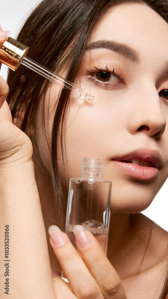 Beautiful young Korean girl applying facial serum, taking care after ...