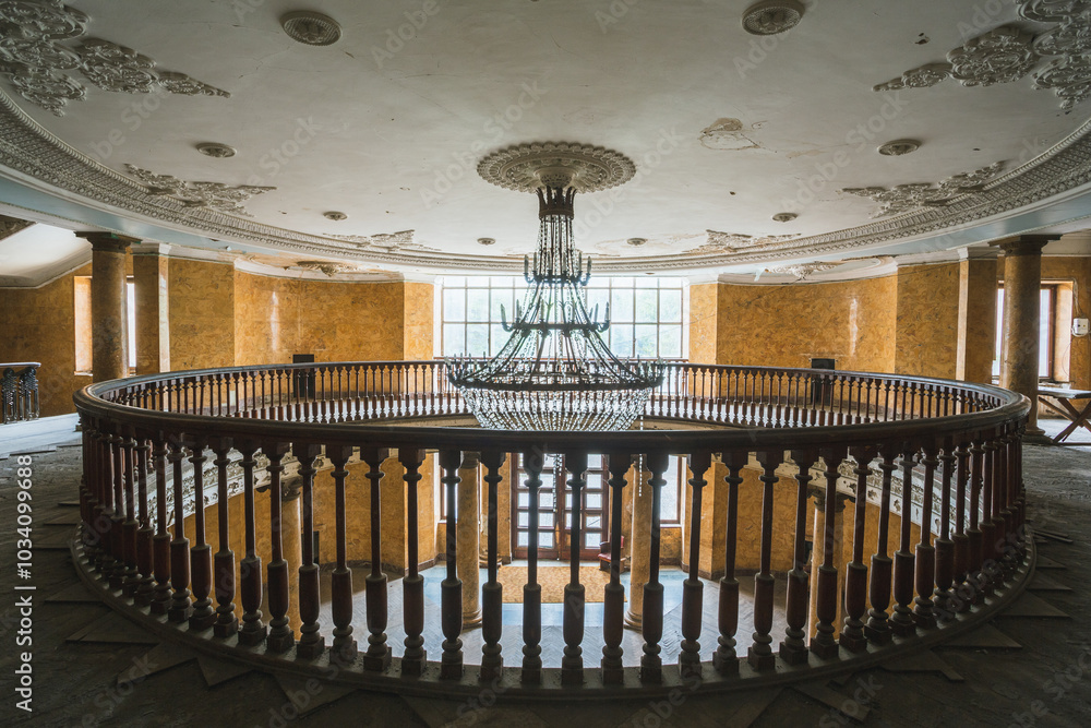two-story hall in an abandoned hotel with a large chandelier and ...