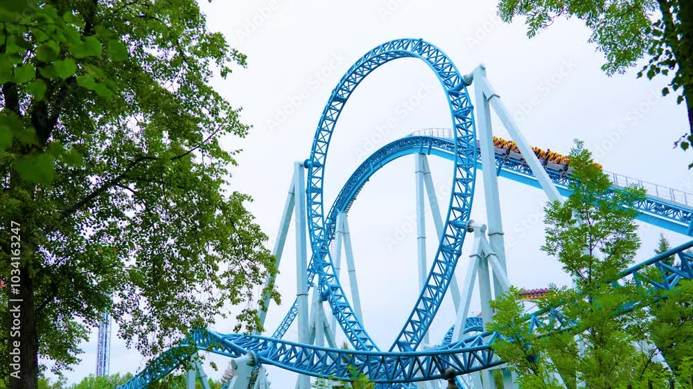 Roller coaster cart with people riding on it goes through an upside ...