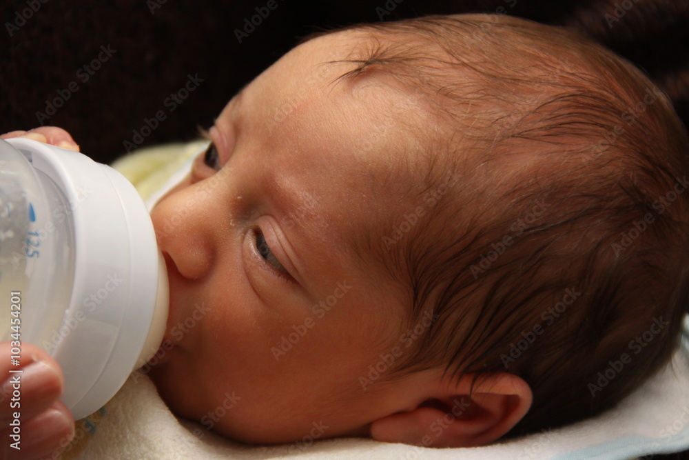 Newborn baby drinking milk from a bottle. Small premature baby feeding ...
