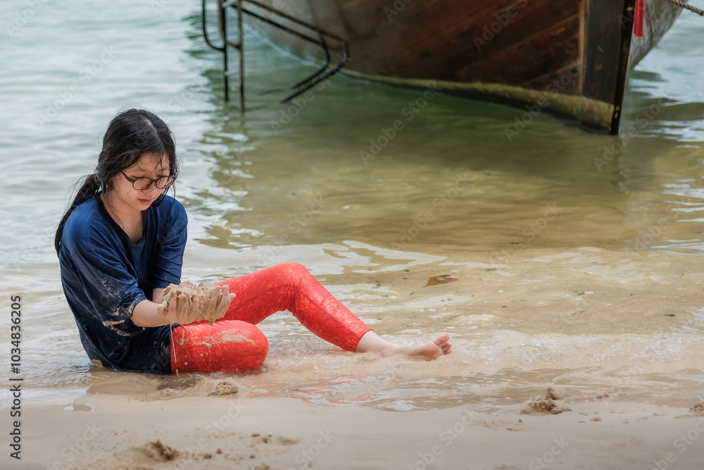 Cute Asian Thai Girl holding a handful of sand on a beautiful beach ...
