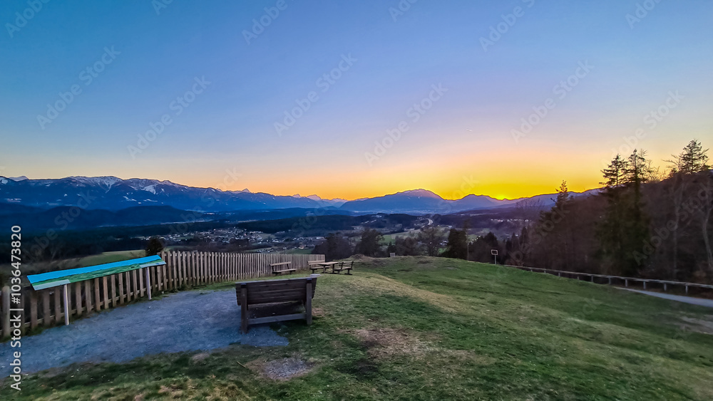 Resting area with wooden chairs and table overlooking fiery sunset ...