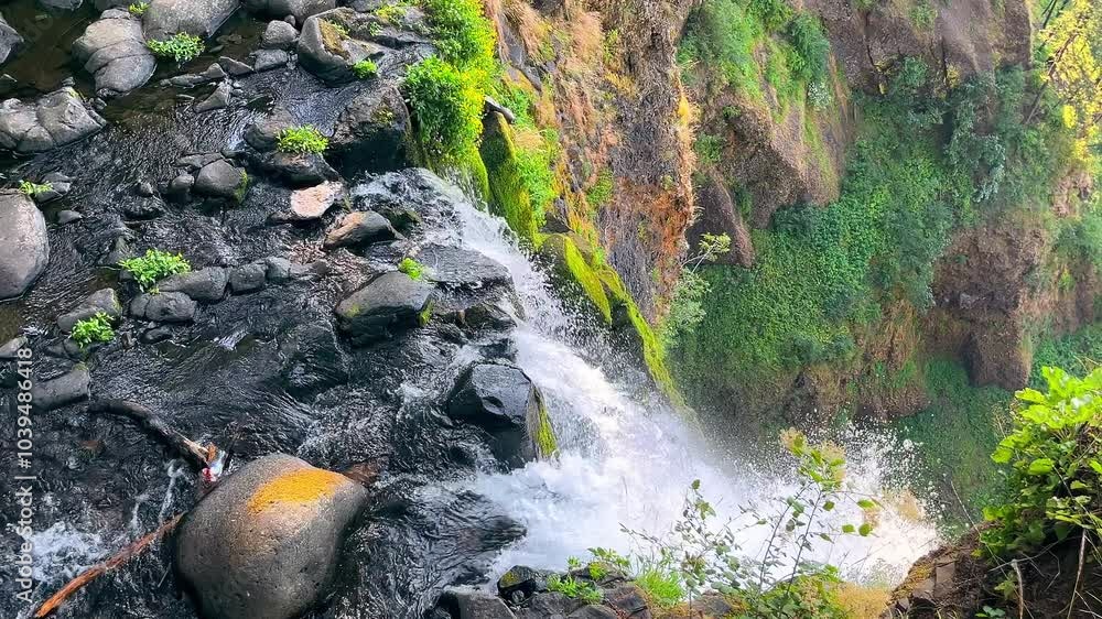 Top view of a waterfall flowing over rocks and greenery. A scenic top ...