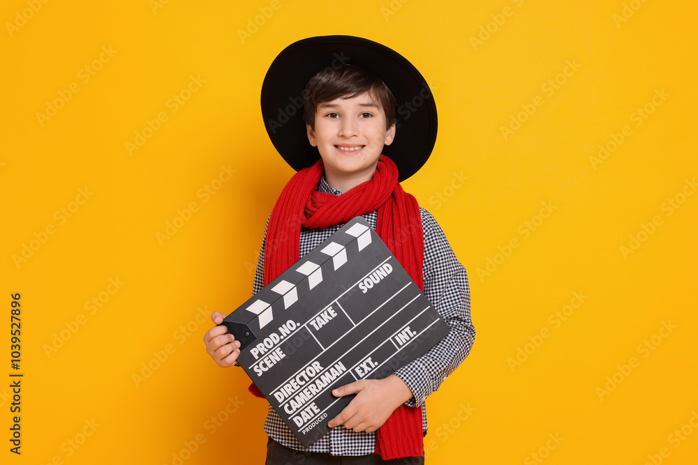 Boy with clapper pretending to be movie director on orange background ...