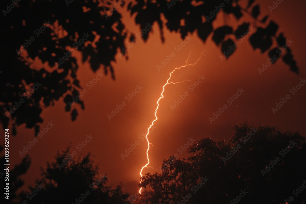 A fierce orange lightning bolt slices through the night sky, striking ...