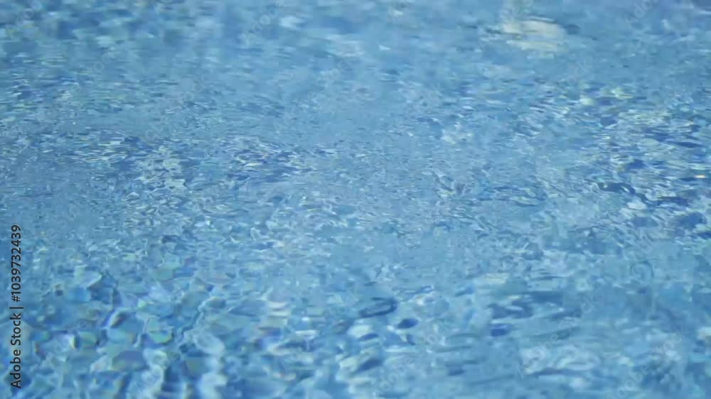 Blue water with sun glare and ripples in the reflection of the pool ...