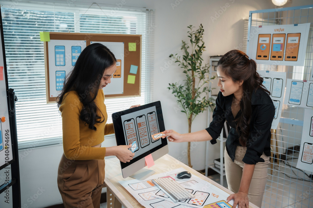 Two asian female uiux designers are discussing over mobile app ...