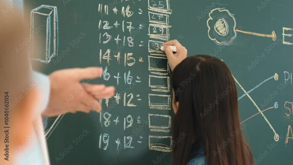 Young asian girl writing math formula at blackboard while standing at ...
