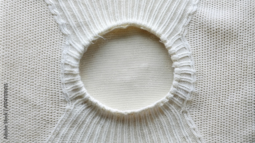 A circular hole in a soft, white knitted fabric, revealing the delicate ...