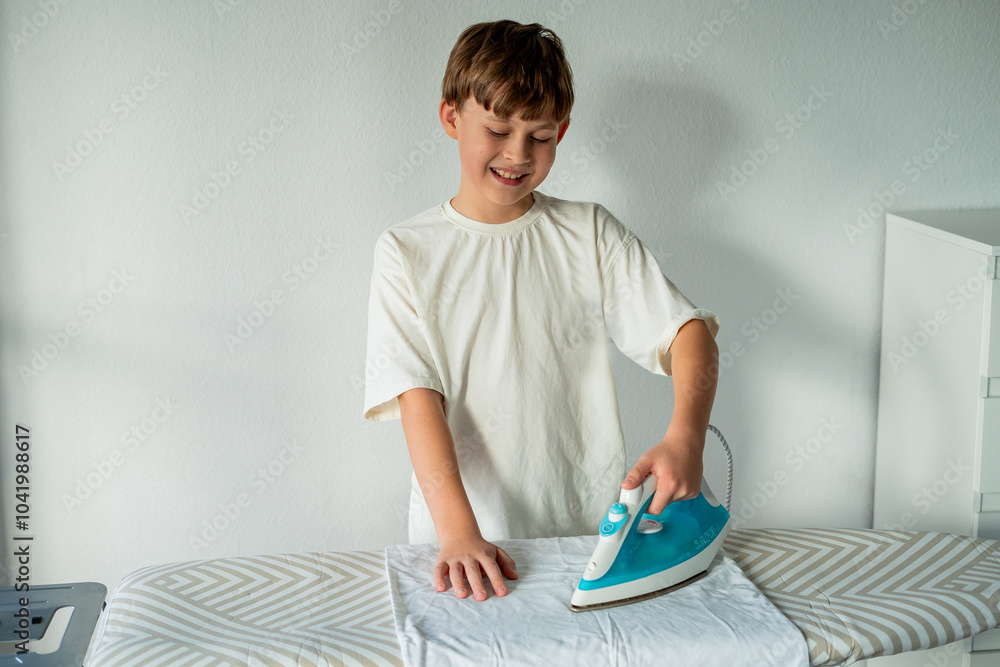 Cute 10 year old boy is doing homework and ironing clothes. Household ...