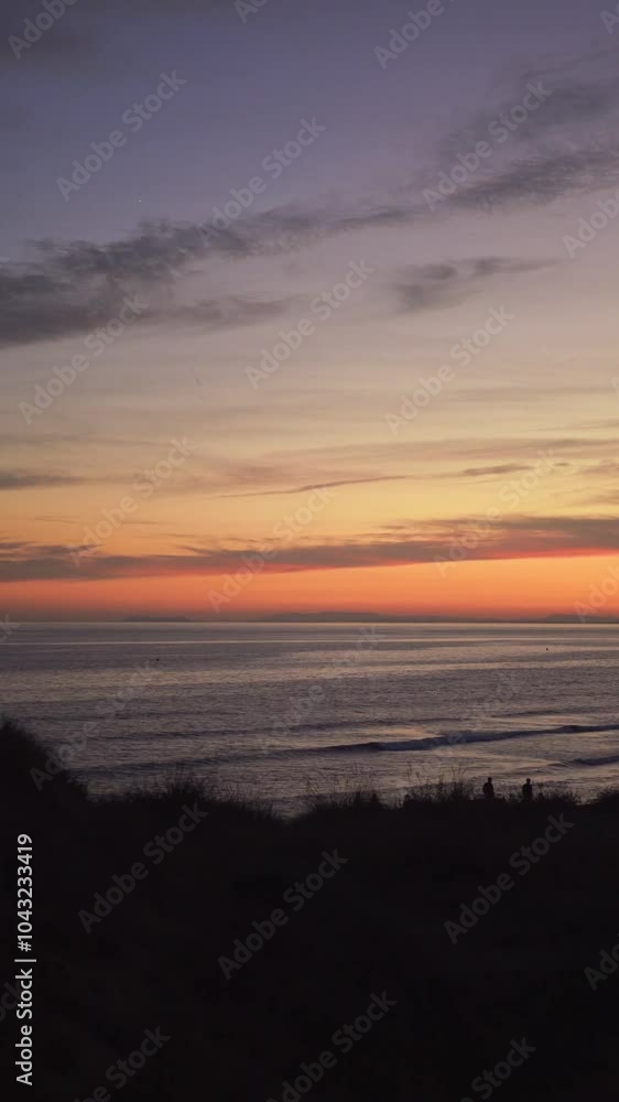 A calm beach scene at sunset, featuring soft pastel colors in the sky ...