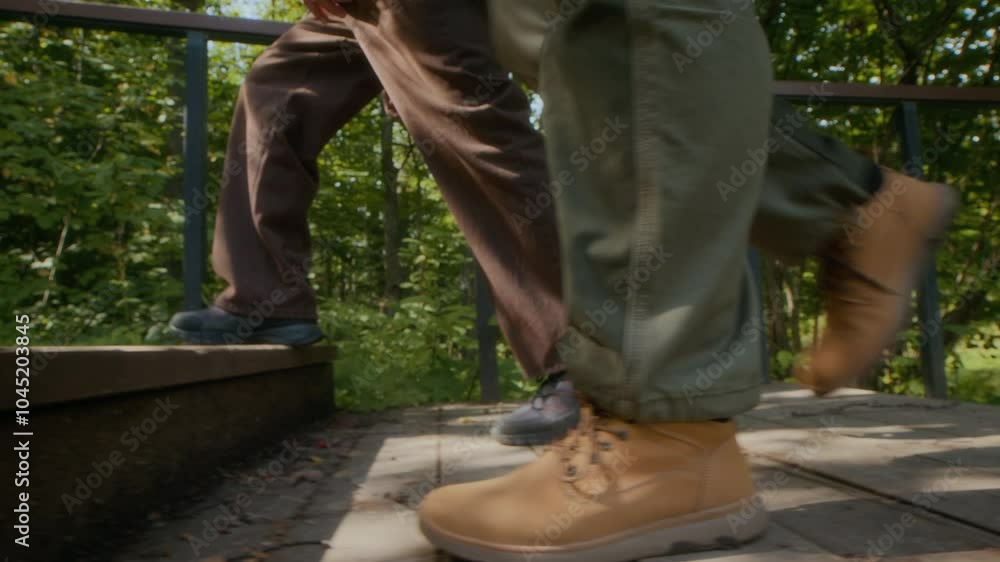 Cropped shot of legs of two unrecognizable travelers walking up wooden ...