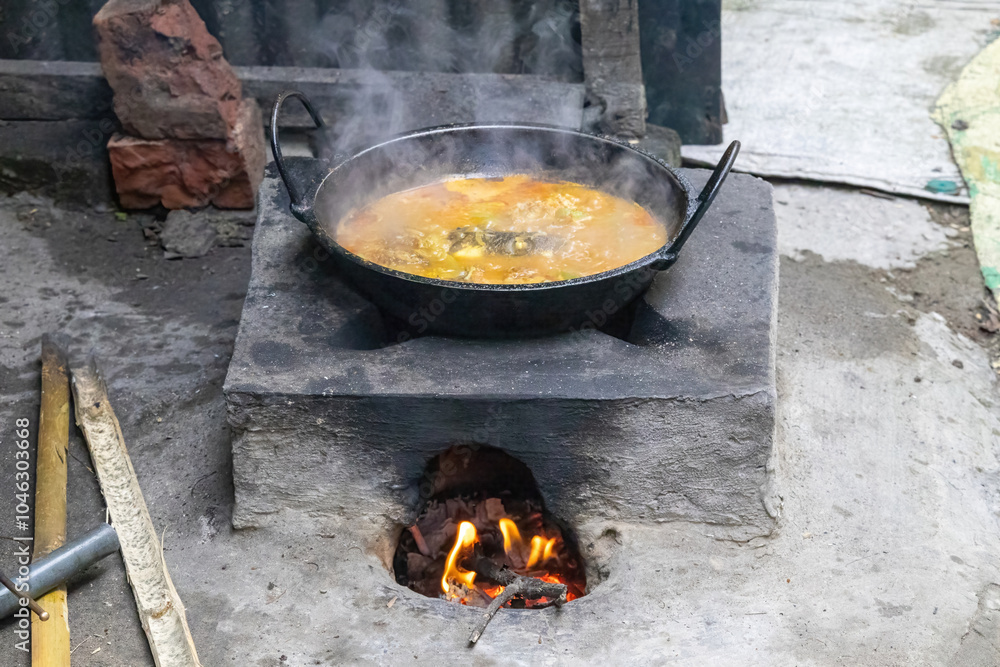 Fish curry cooking on a traditional mud stove. Village kitchen in ...