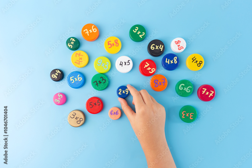 Child hands arranging colorful bottle caps with multiplication problems ...