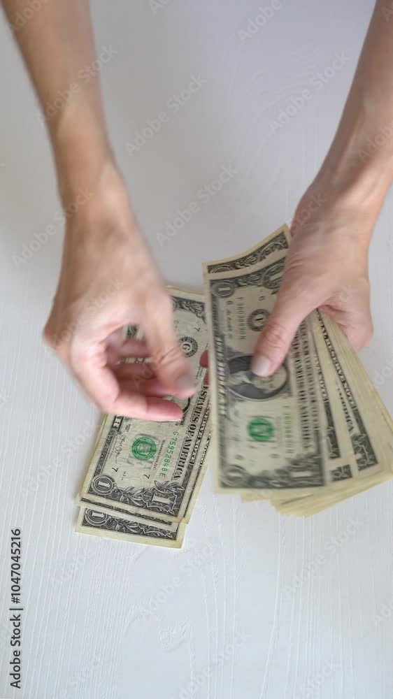 Vertical footage of a woman’s hands holding and counting 1 dollar bills ...