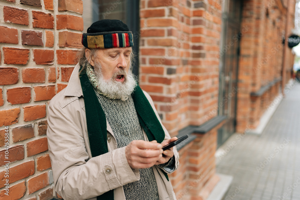Elderly homeless man looking surprised during using smartphone while ...
