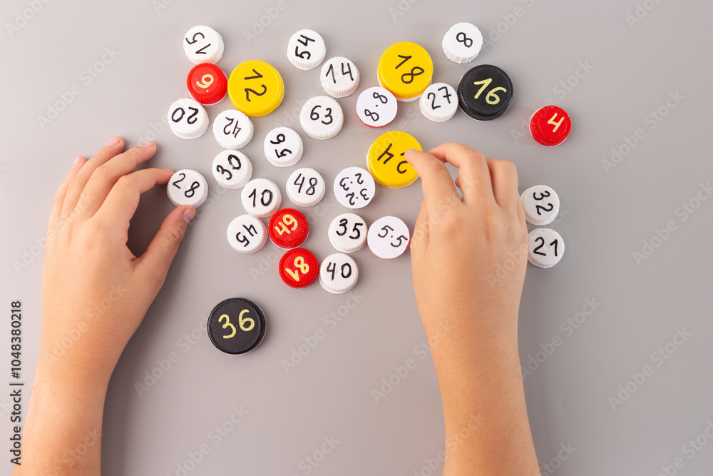 Children hands arranging plastic bottle caps with numbers and ...
