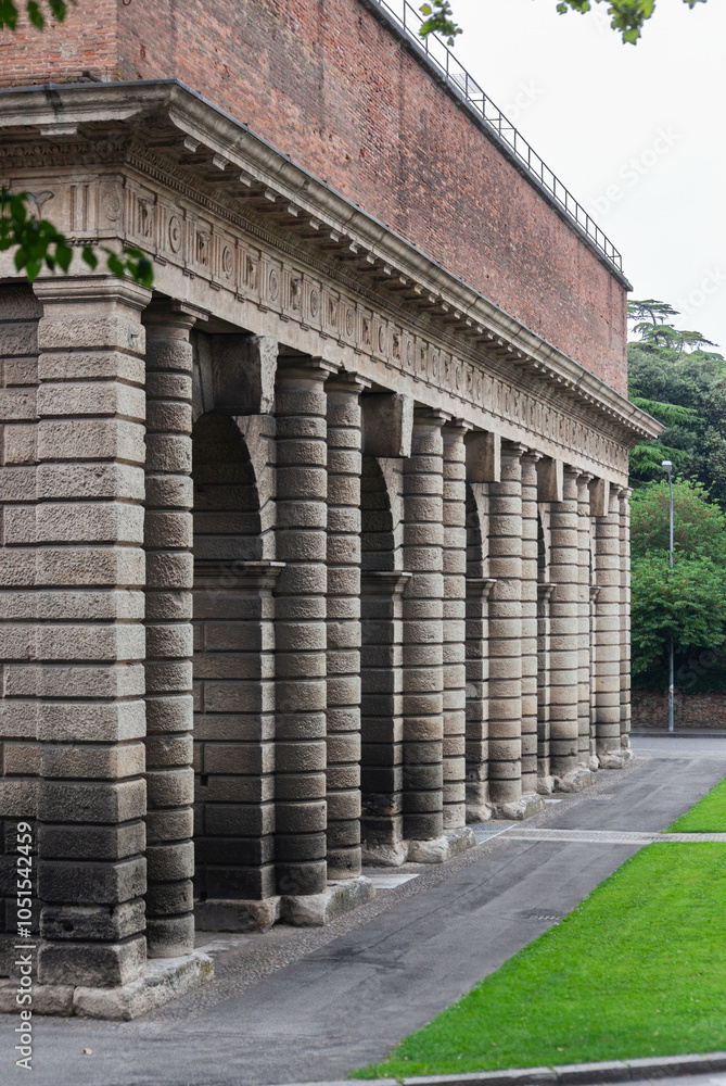A grand colonnade with robust, textured stone pillars stands in quiet ...