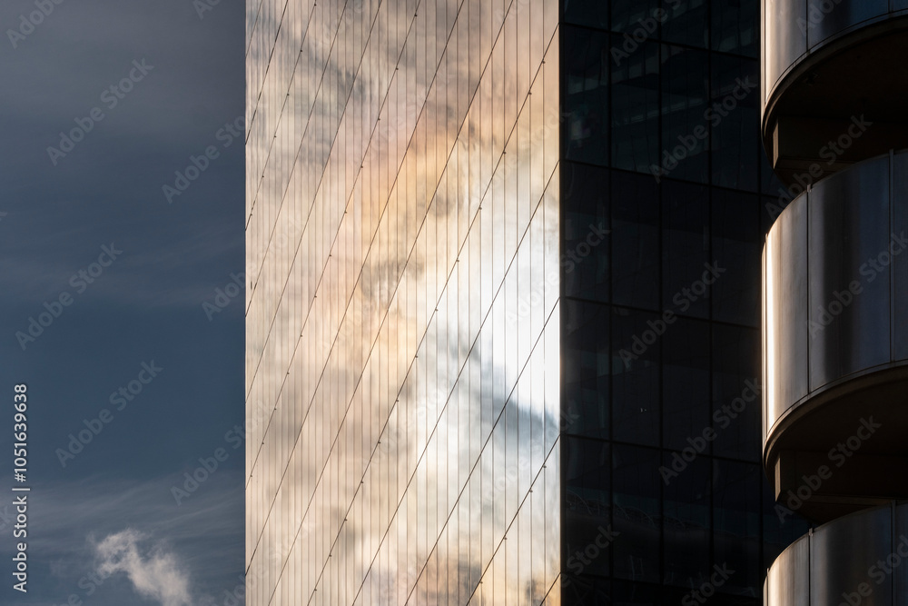 The image captures a modern skyscraper with sunlight reflecting off its ...
