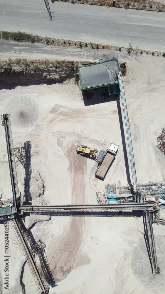 Vertical real-time footage of front loader loading dumper truck with ...