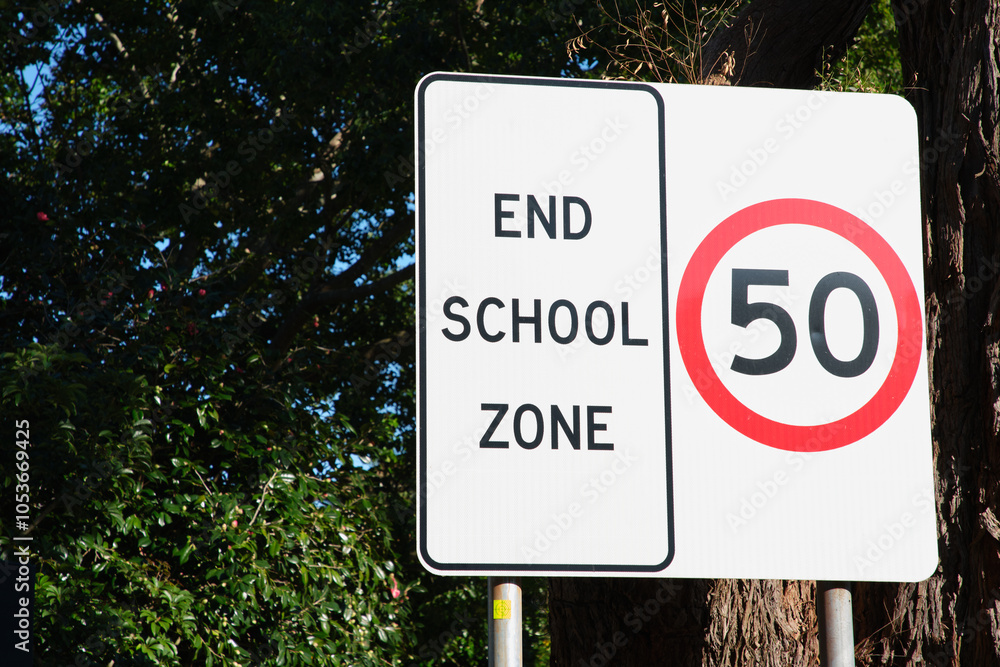 road sign indicating the speed limit and end school zone with leafy ...