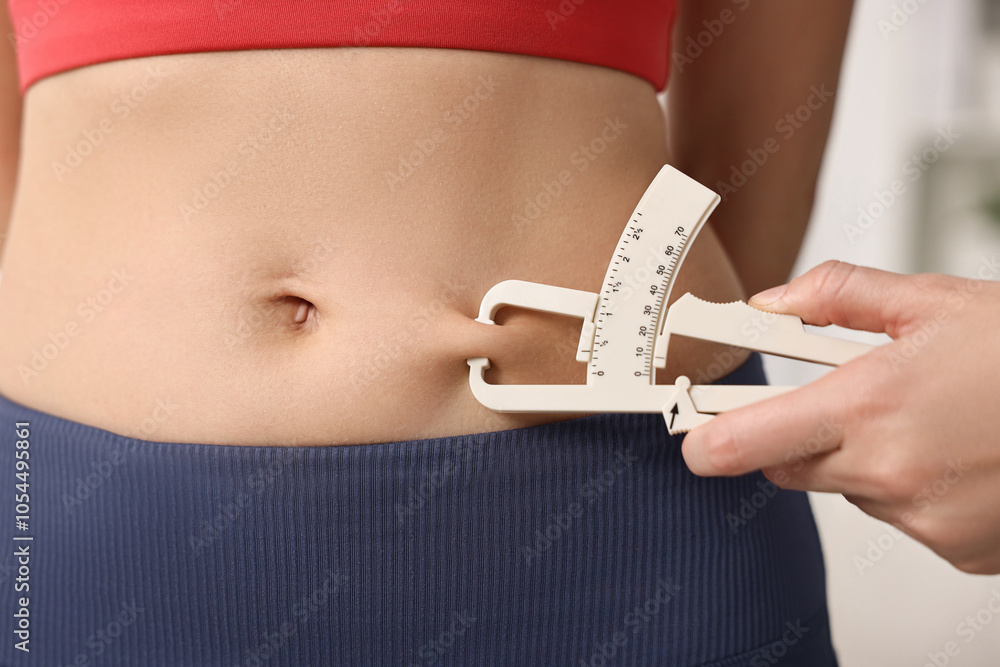 Doctor measuring woman's body fat with caliper in clinic, closeup ...