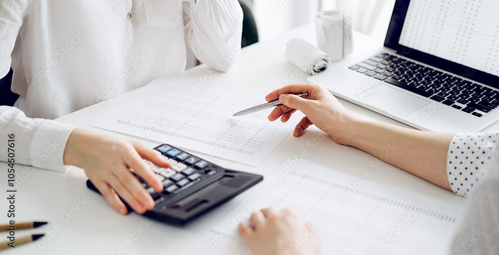 Accountant using a calculator and laptop computer for counting taxes ...