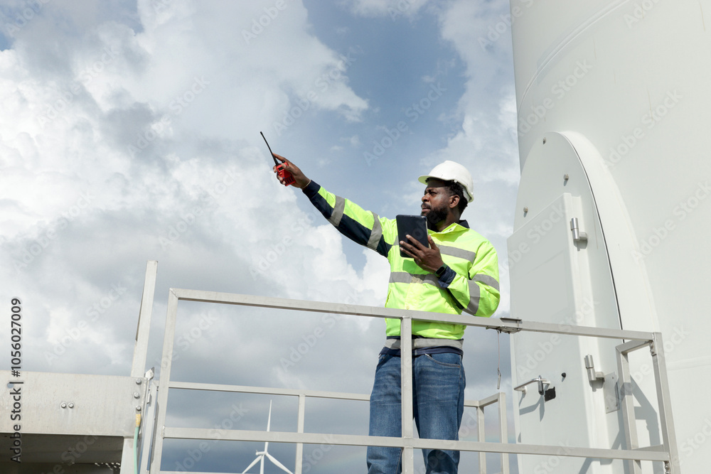 African engineer with safety vest and helmet using walkie talkie at ...