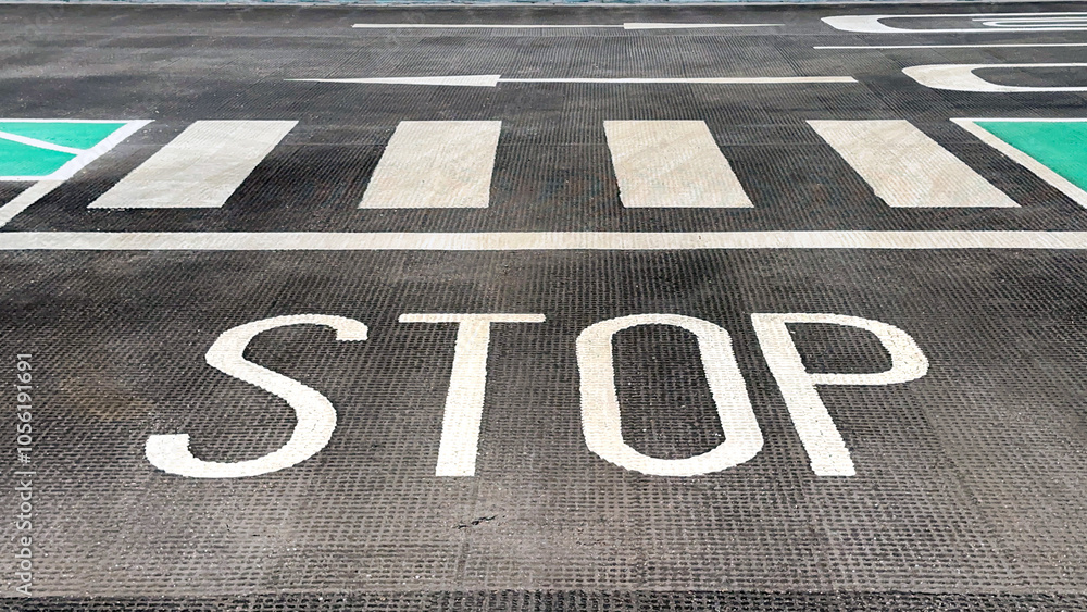 Stop sign and pedestrian crossing on the floor of a car park. No people ...