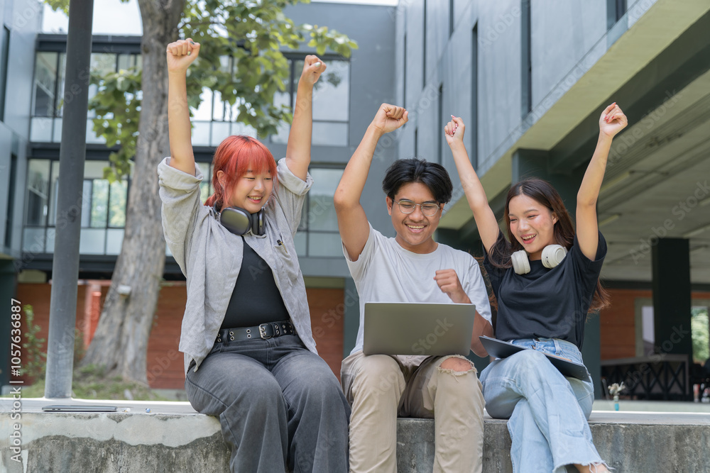 Three cheerful asian students raising their arms while celebrating ...