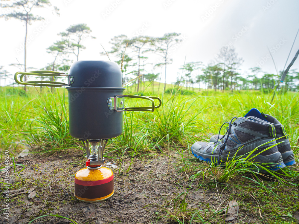 Camping with portable gas stove cooking pot setup on the ground beside ...