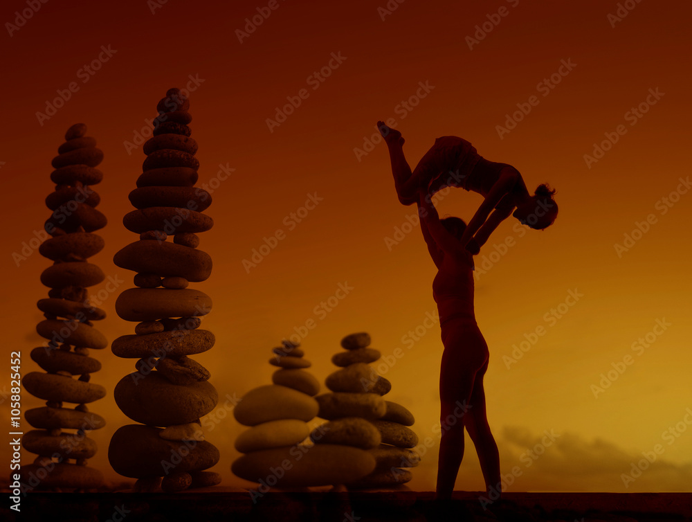 Silhouette of fit sporty couple practicing acrobatic yoga with partner ...