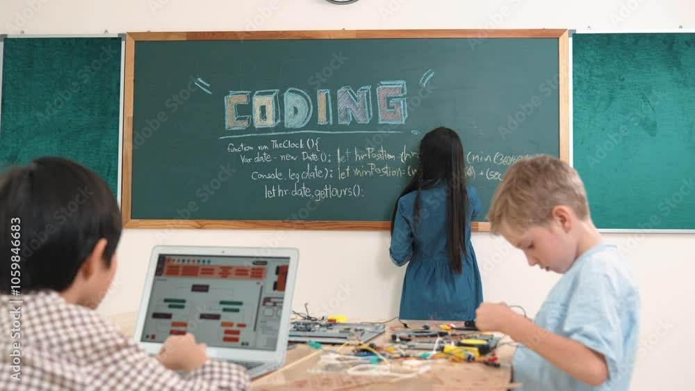 Asian boy coding program while caucasian friend fixing electric board ...