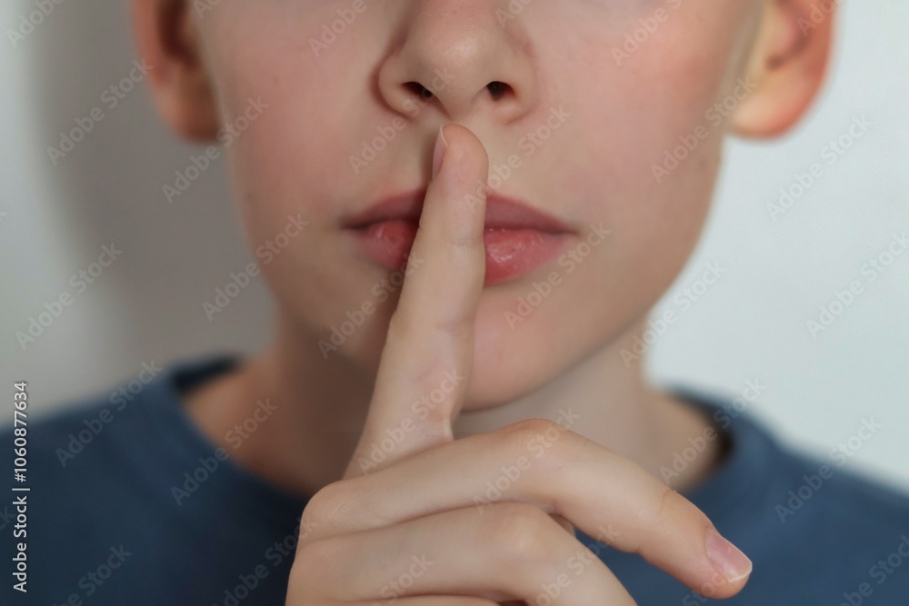 A boy making the "shhh" sign; A boy putting his finger to his lips ...