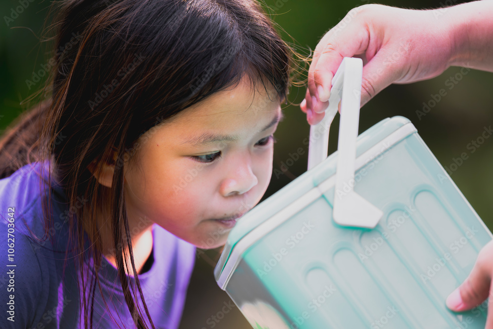 Close-up portrait of a little girl drinking water through a straw from ...