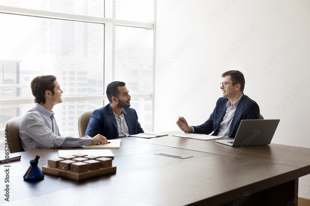 Diverse team of male business leaders in formal suits talking at table ...
