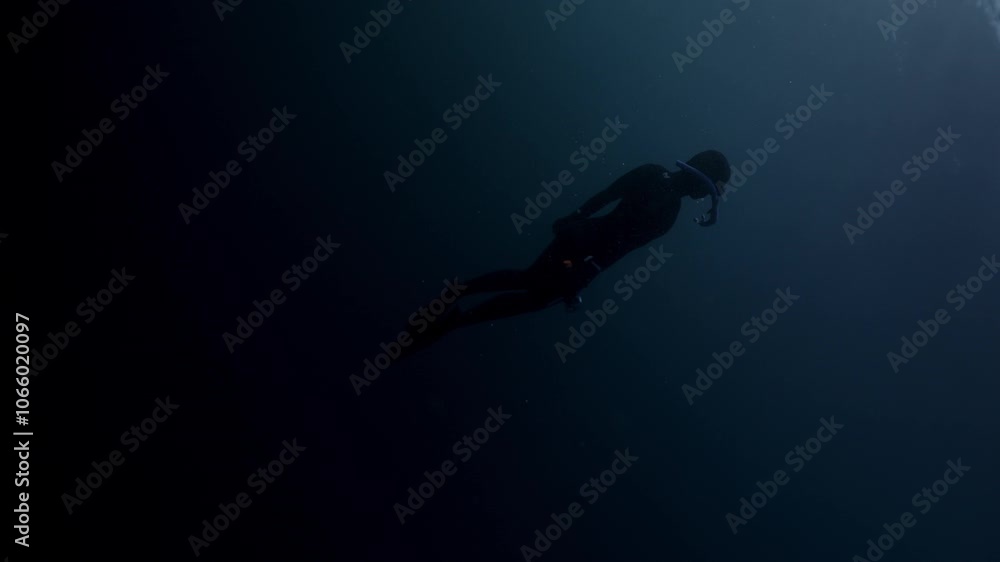 Man diver freediver in neoprene costume float up from deep blue ocean ...