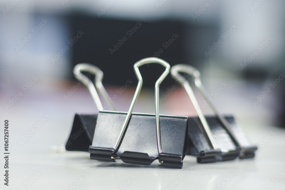 close-up view of several black binder clips arranged in a row on a ...