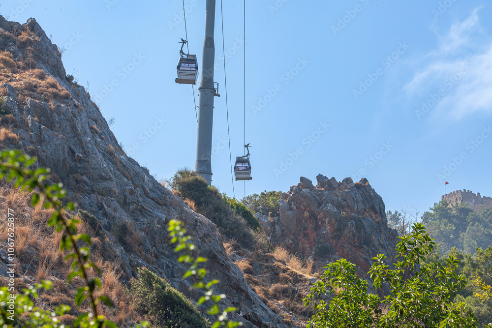 cable car in the mountains on a blue cloudy sky background. Communication tower on a cable car ...