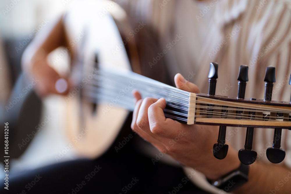 man’s hand skillfully strumming the strings of an oud, capturing the ...