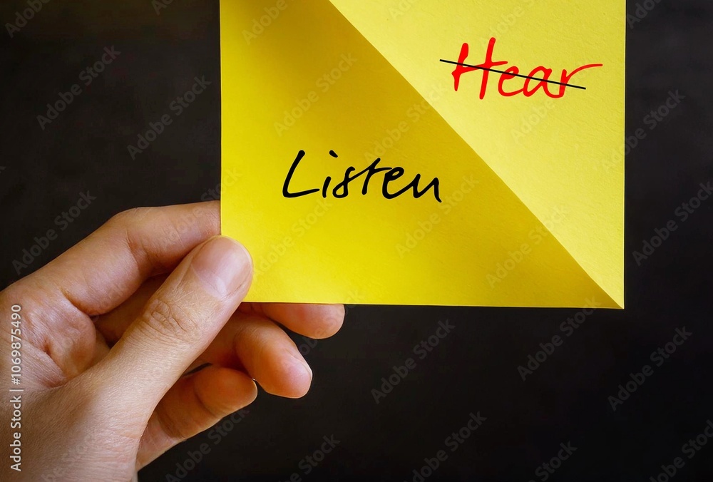 Hand holding paper note with handwritten text HEAR replaced with LISTEN ...