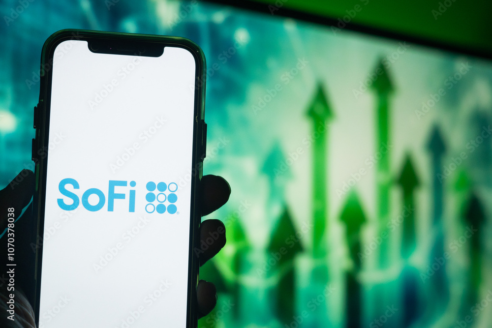 Hand Holding Phone with SoFi (SOFI) Logo and Monitor in the Background ...