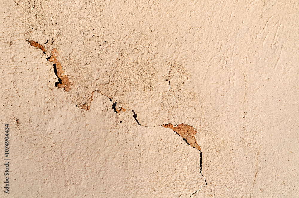 Peeling stucco on the old rough wall surface, cracks on the stucco ...