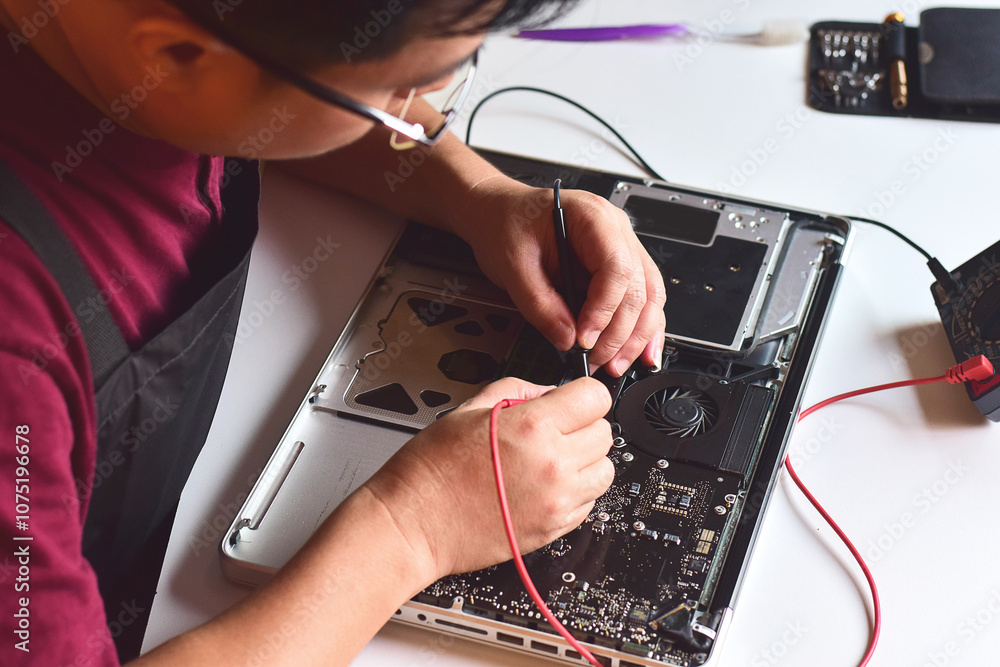 Computer technician wearing glasses A laptop motherboard repairman is ...
