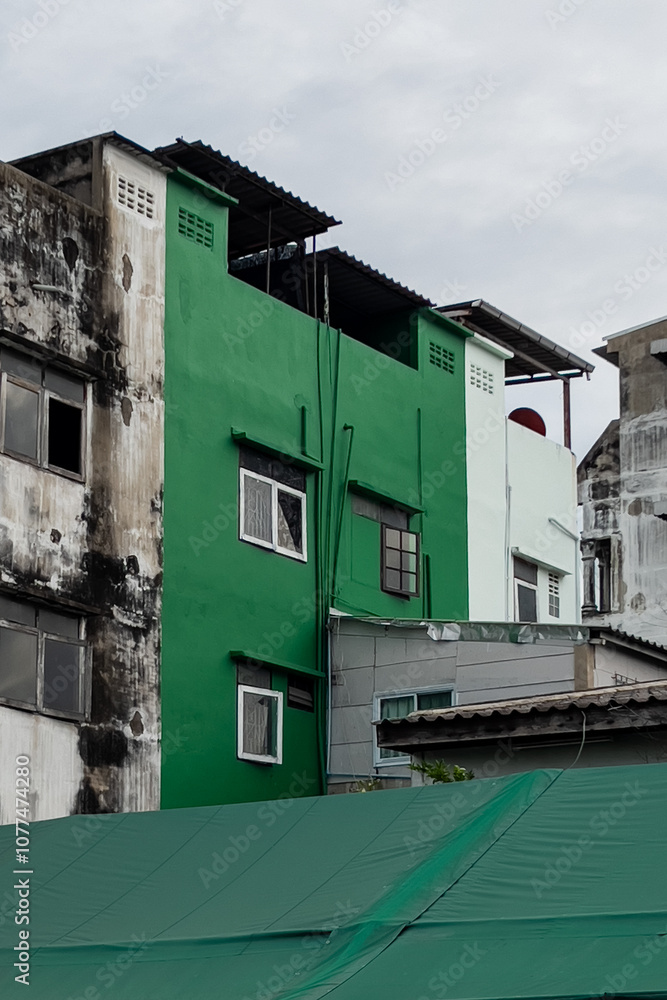 Fresh green paint on a building above a green tarp roof in Bangkok ...