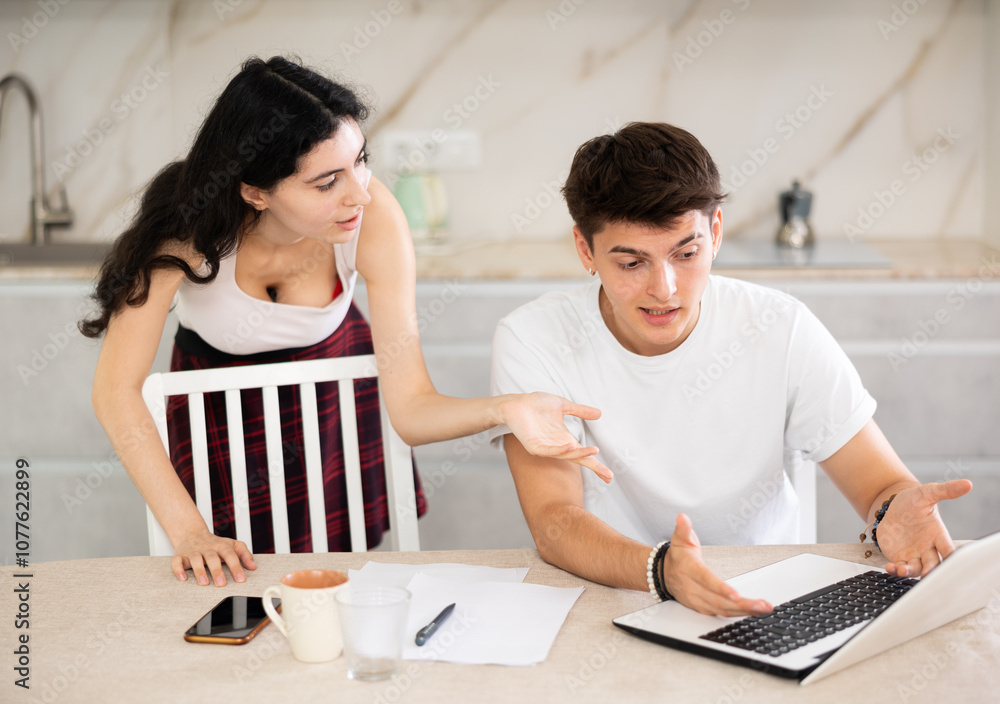 Sad and tired freelancer husband works at home on laptop and listens to ...